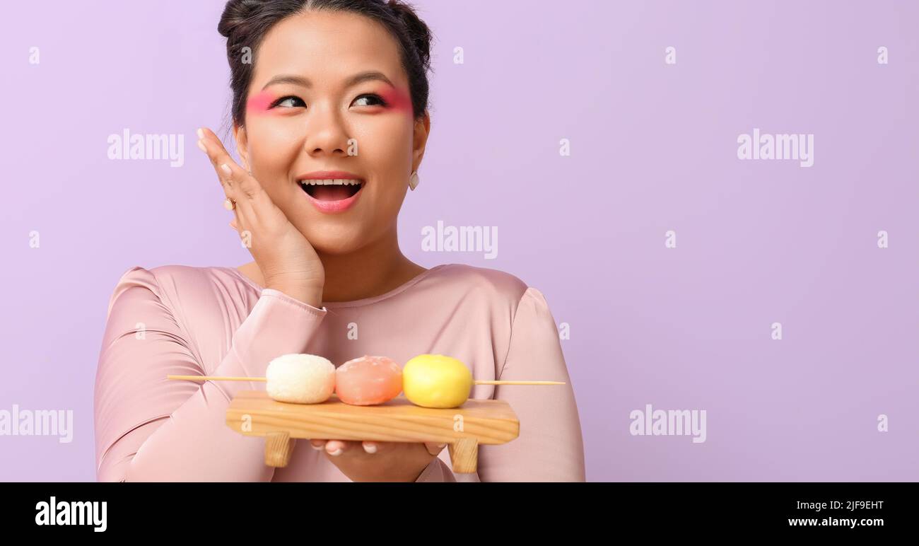 Happy Asian woman with tasty Japanese mochi on lilac background Stock ...