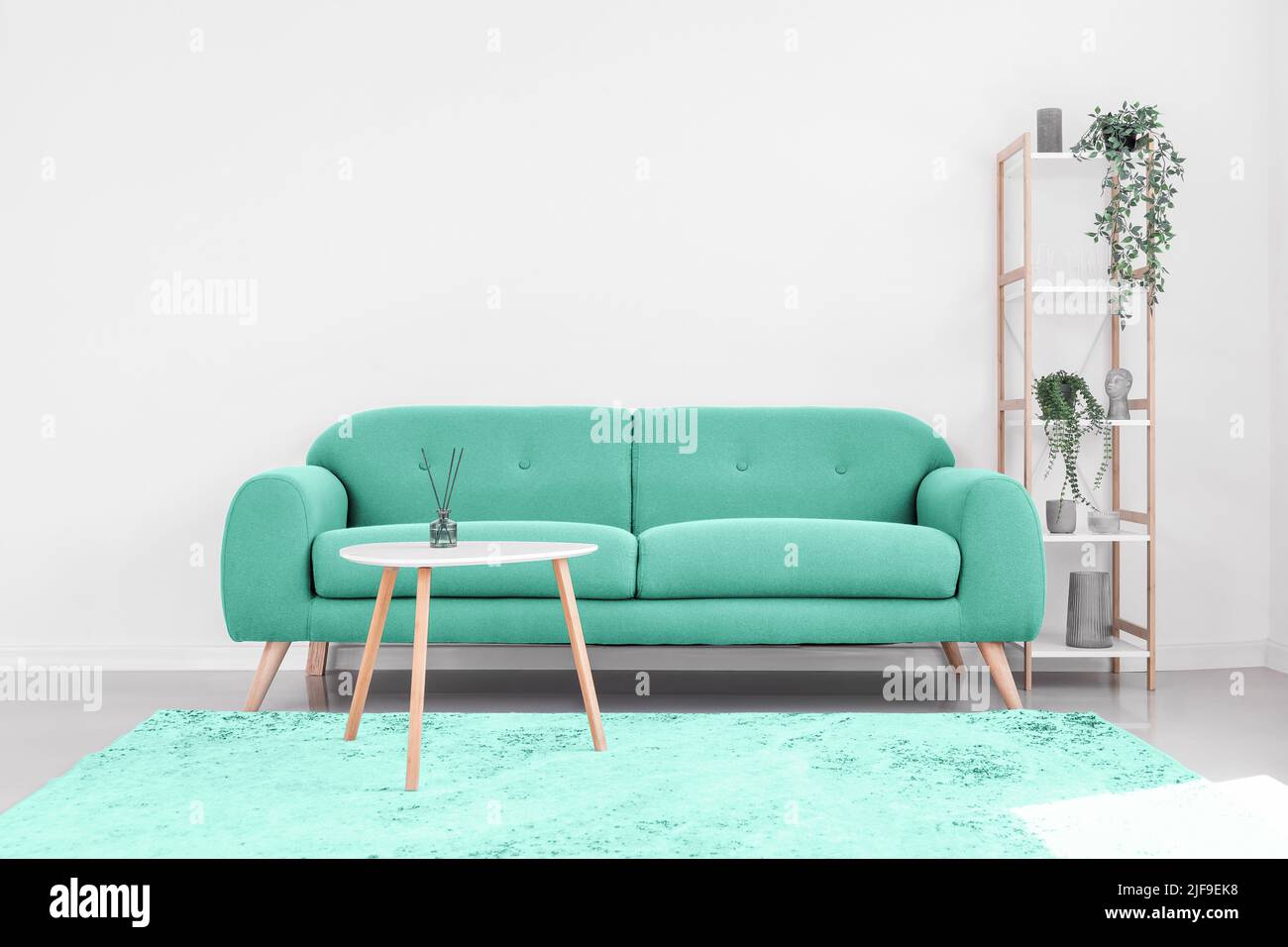 Stylish mint sofa with table and rack near light wall in room Stock ...