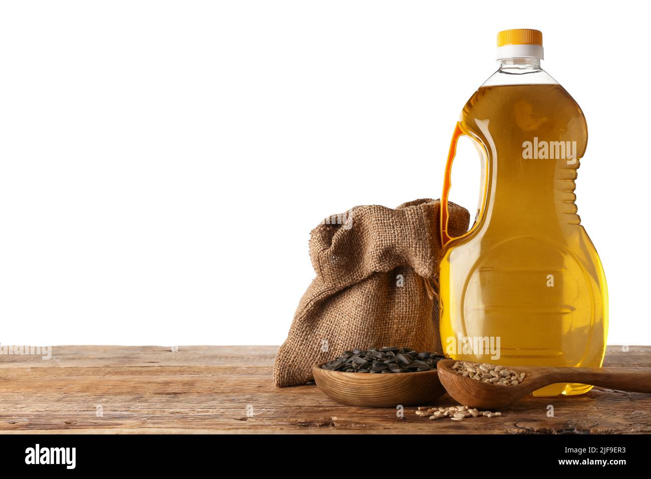 Bottle of fresh oil, sack bag and sunflower seeds on wooden table ...