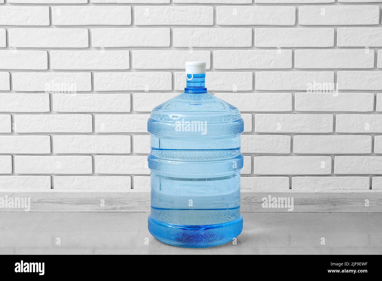 Bottle of clean water on floor near light brick wall Stock Photo - Alamy
