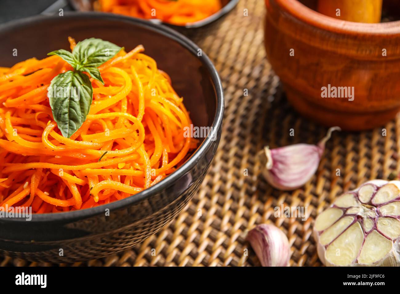 Bowl with spicy carrot salad on wicker mat, closeup Stock Photo - Alamy