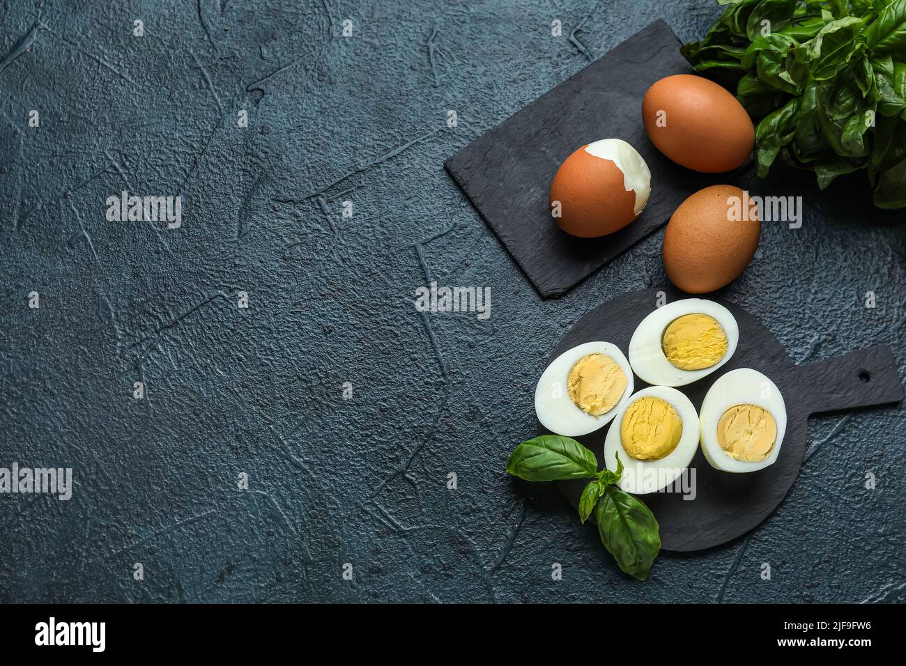 Composition with board of boiled chicken eggs and basil on dark ...