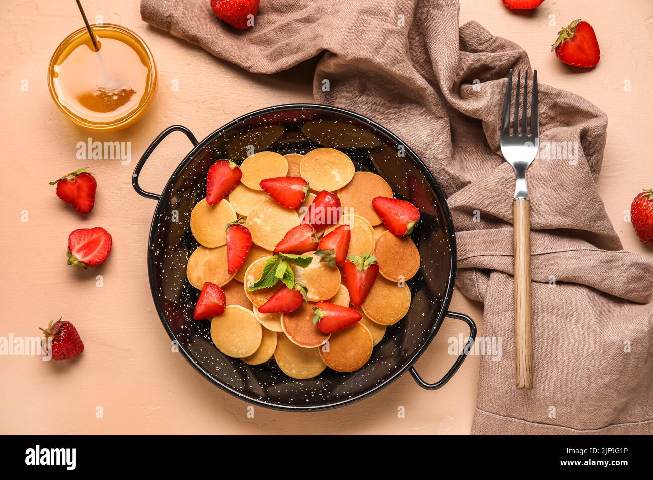 Composition with frying pan of mini pancakes, strawberry and bowl of ...
