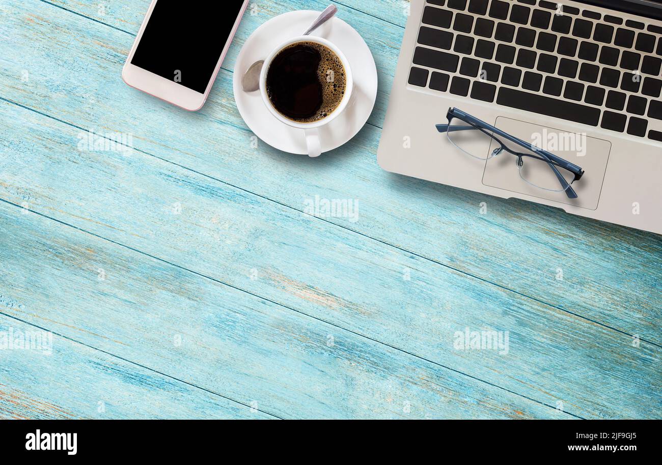 Laptop computer, glasses and cup of coffee on wood table top view with ...