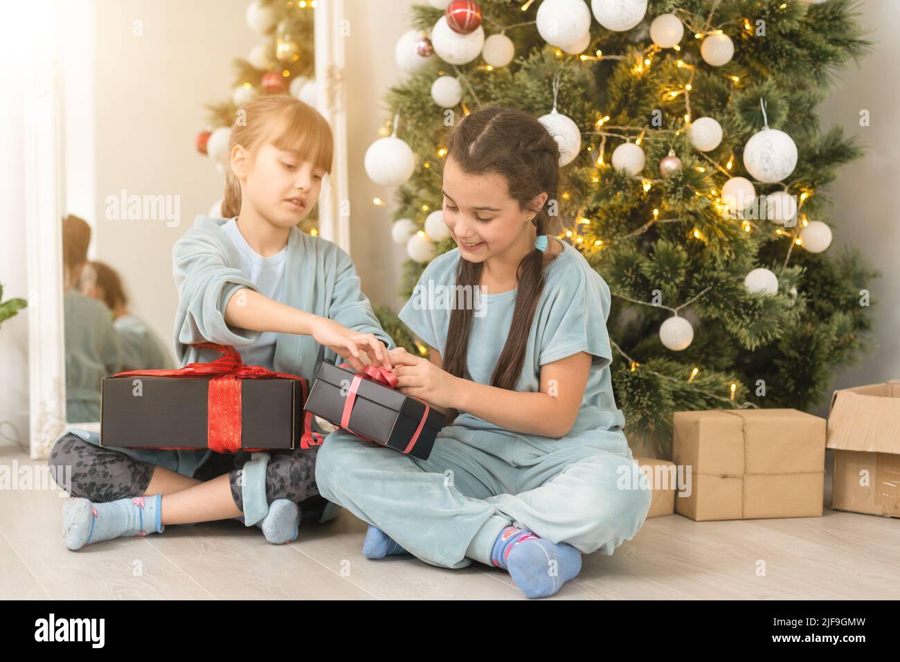 Two cute little girls under Christmas tree. Children under Christmas ...