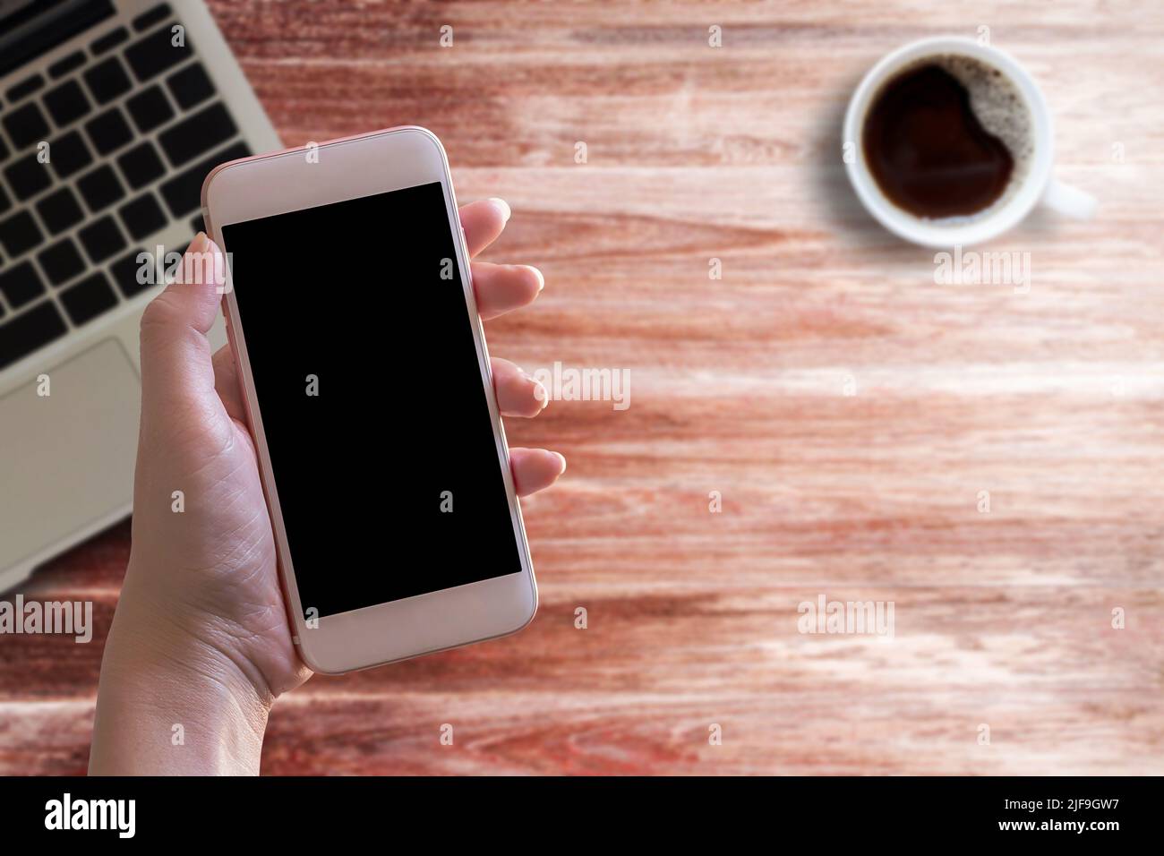 Hand holding mobile smart phone with office desk vintage wood working ...