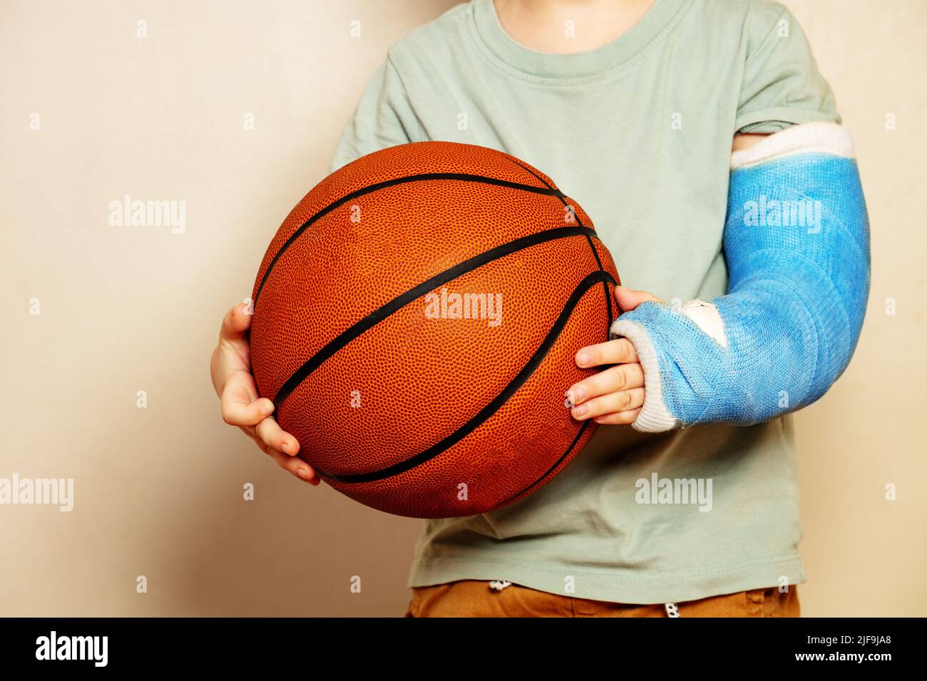 Big basketball ball in hands of boy with broken hand cast Stock Photo ...