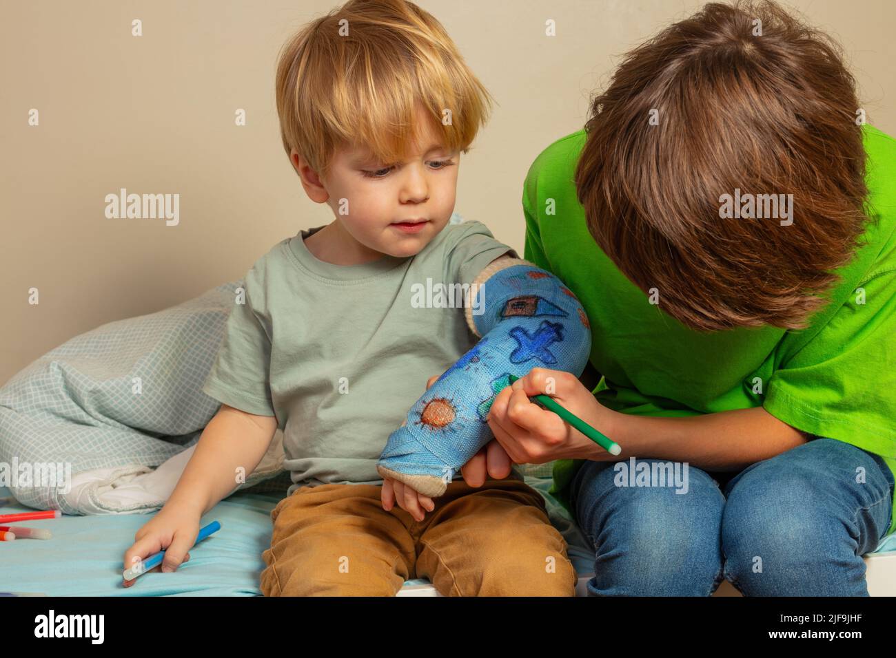 Little boy making drawings with felt-tip pen on broken hand cast Stock ...
