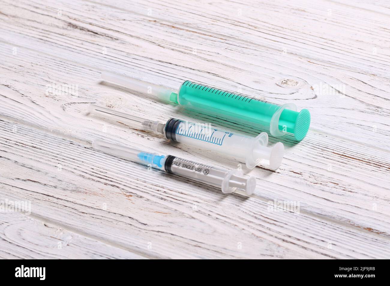 Top view of syringes of different sizes on wooden background. Medical ...