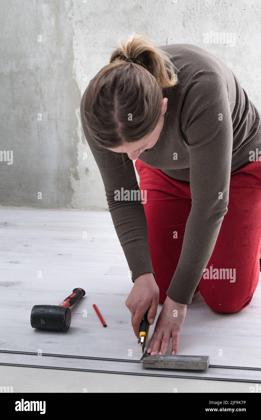Female master draws a pencil line on the board, installing quartz vinyl ...