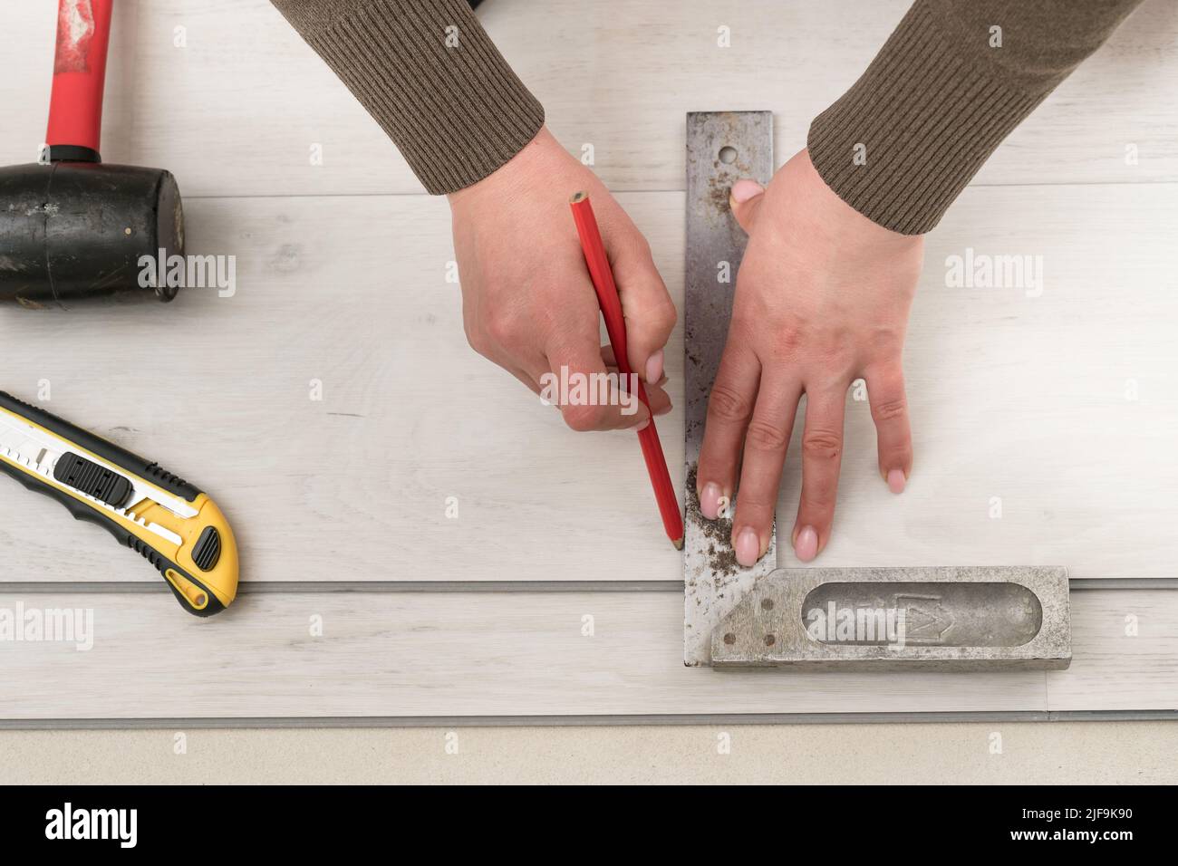 Female master draws a pencil line on the board, installing quartz vinyl ...