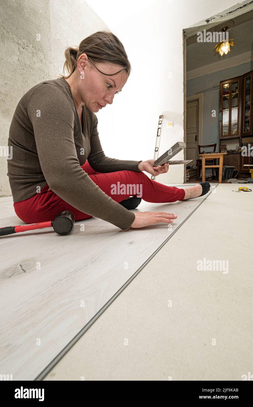 Installing a quartz vinyl floor, a woman performs installation work ...