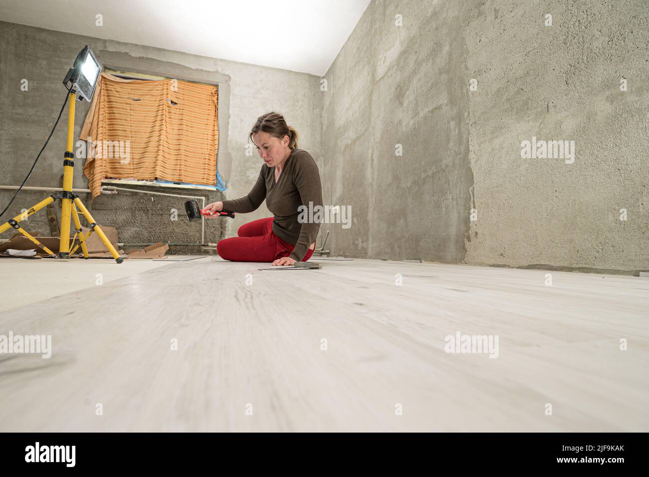 Woman installs quartz vinyl flooring at home, exhausted woman from work ...