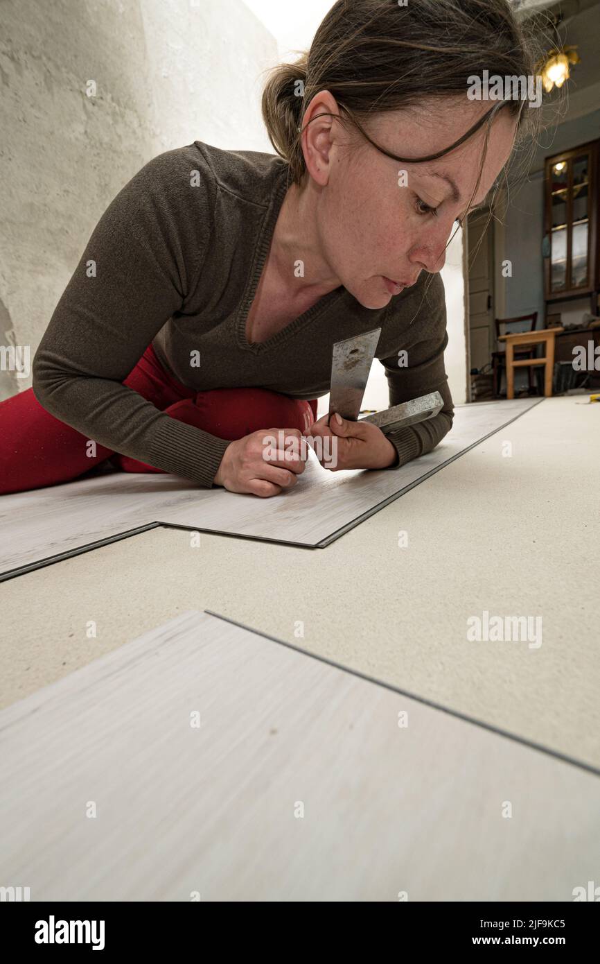 Installing a quartz vinyl floor, a woman performs installation work ...