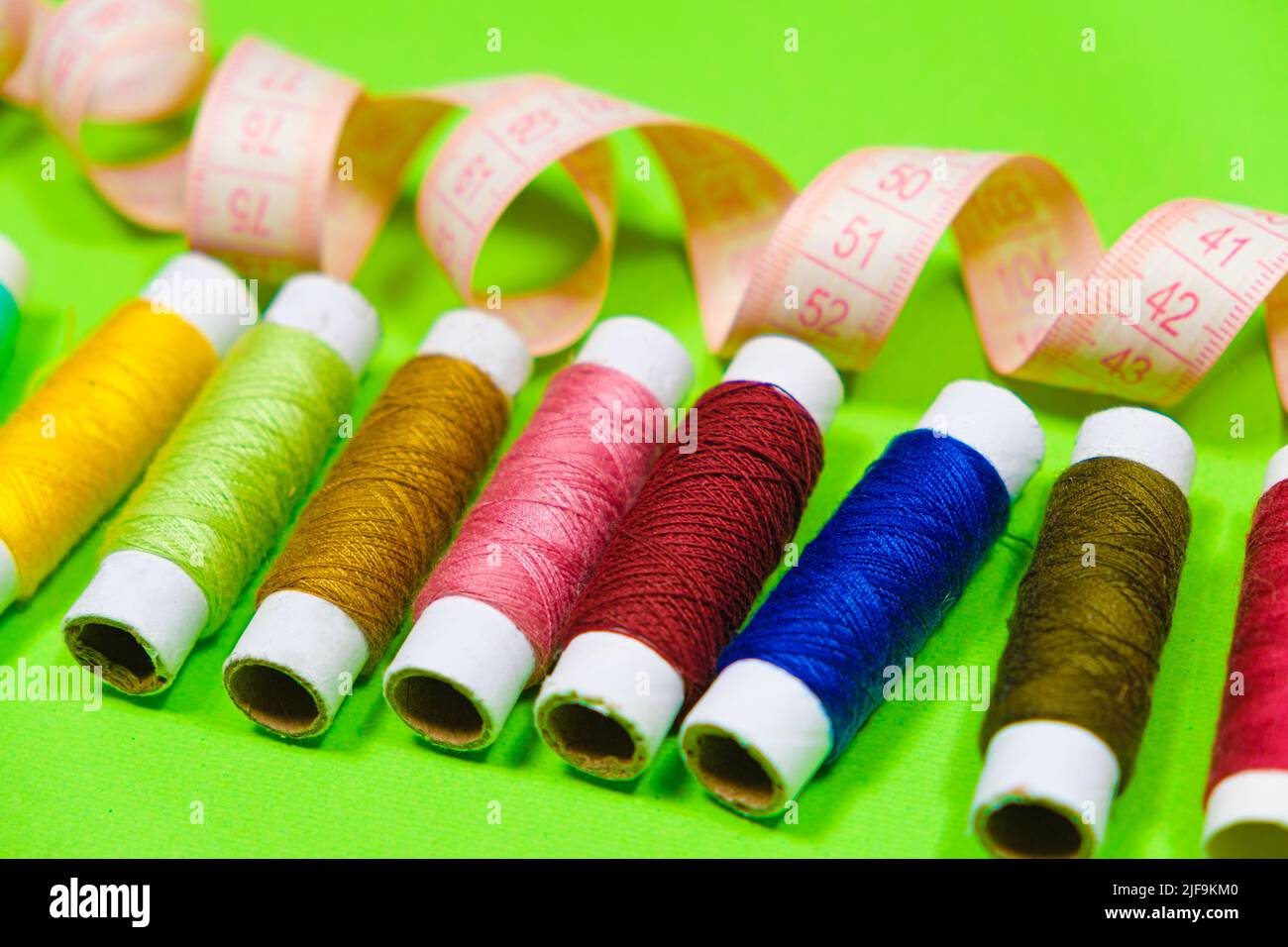 A set of multi-colored threads for sewing and a measuring tape on a ...