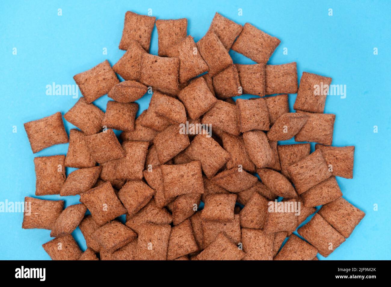Sweet breakfast cereal dry - chocolate pads made of cereals on a blue ...
