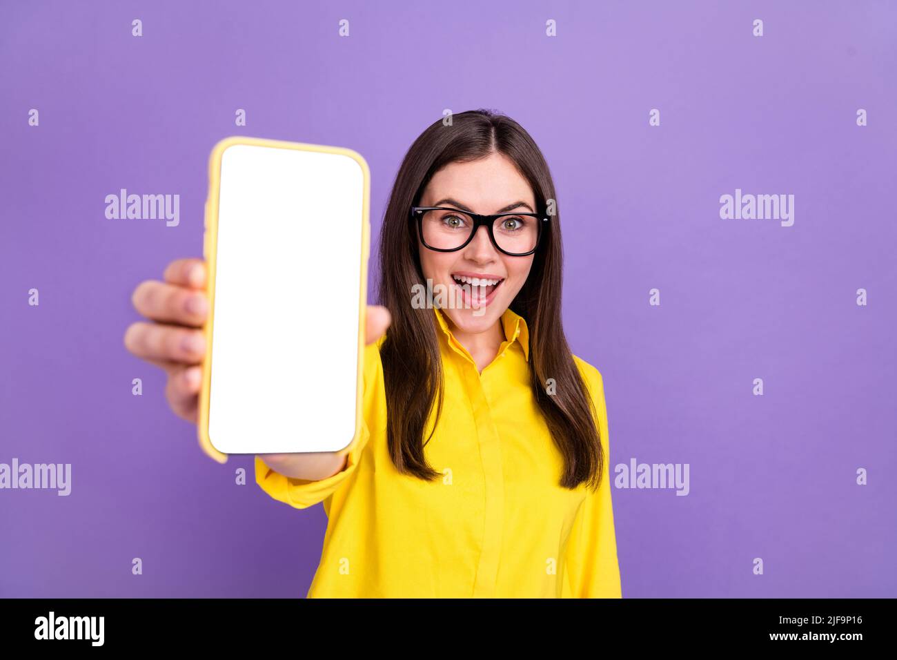 Portrait of beautiful trendy amazed girl demonstrating device gadget ...