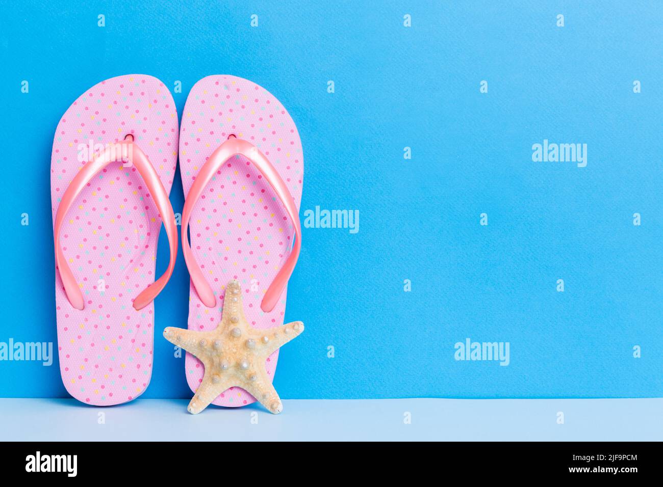 Beach accessories. Flip flops and starfish on colored background. Mock ...