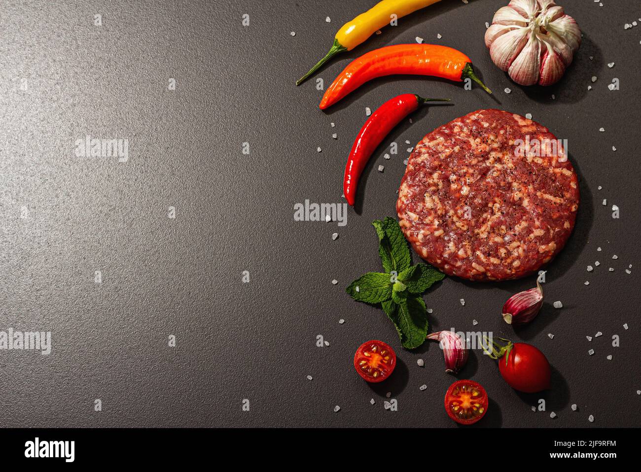 Raw steak cutlets from minced beef meat on black stone background ...