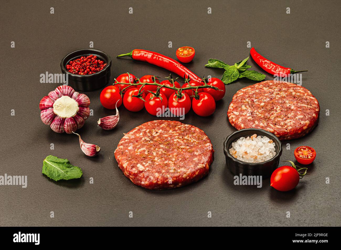 Raw steak cutlets from minced beef meat on black stone background ...