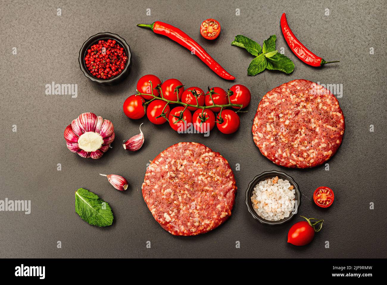 Raw steak cutlets from minced beef meat on black stone background ...