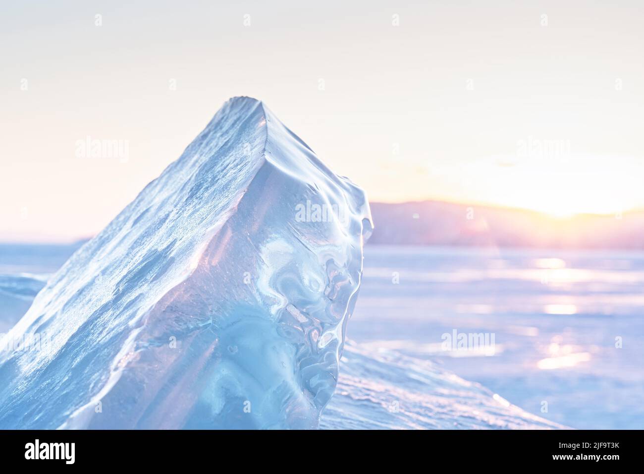 Winter landscape with ice hummocks glittering in the sun and mountains ...