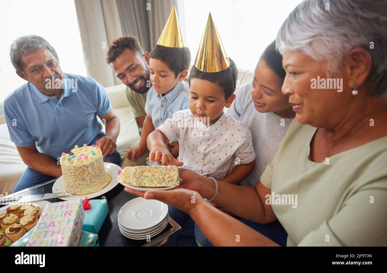 Mixed race family celebrating a birthday and having come cake at home ...