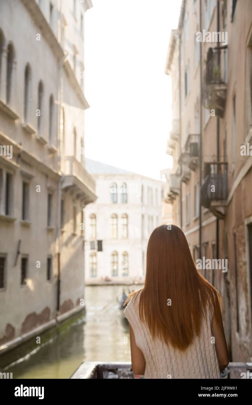 back view of woman with red hair near blurred medieval buildings in ...