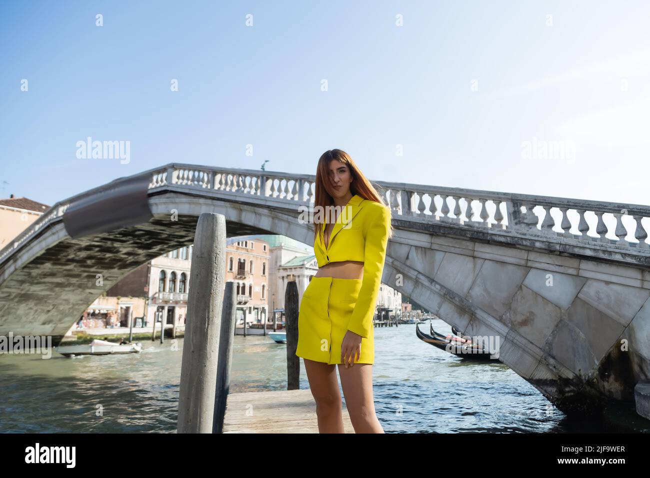 stylish woman in yellow suit posing near bridge on background in Venice ...