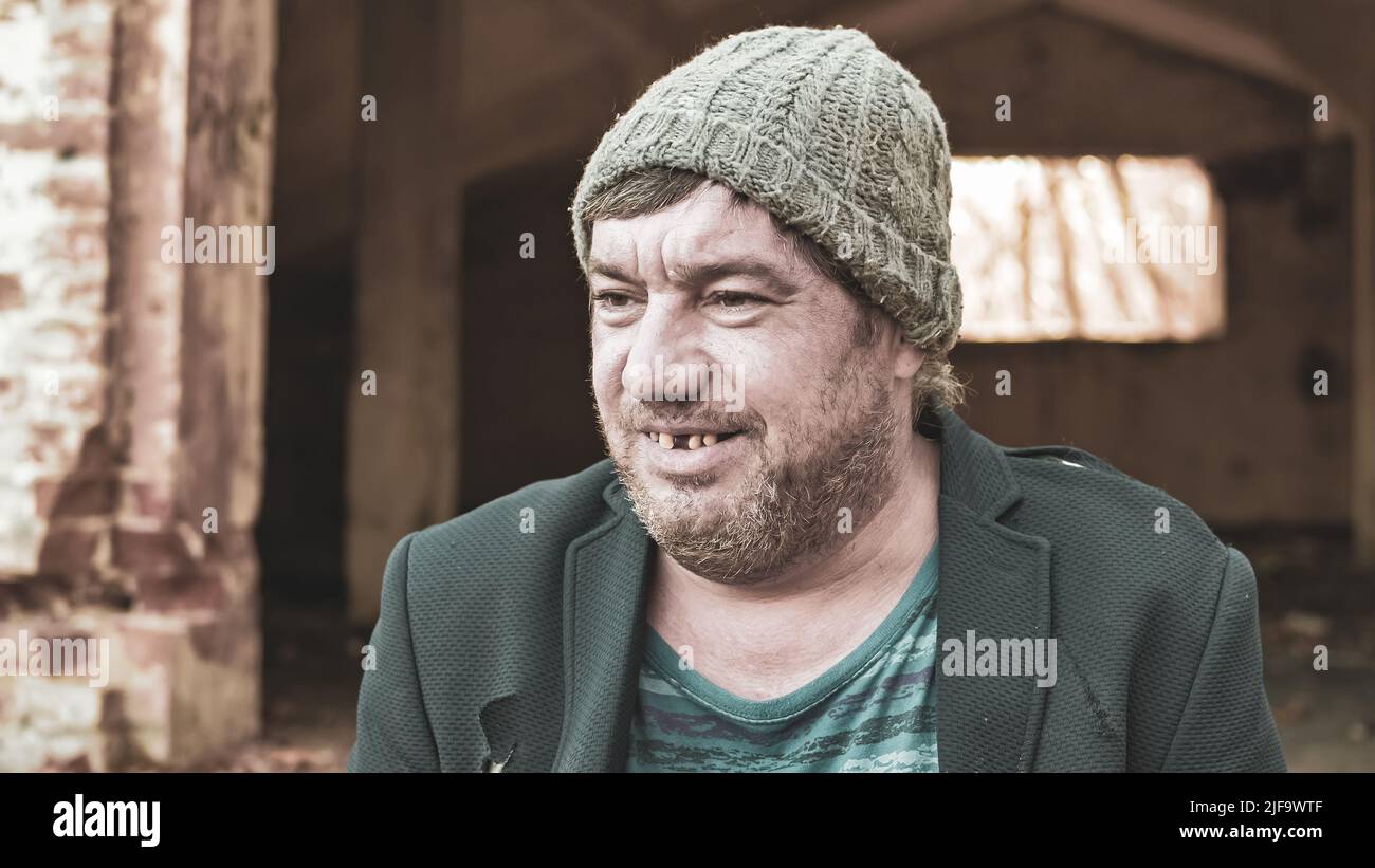 a poor homeless man in a hat and suit smiles looking at the camera in ...