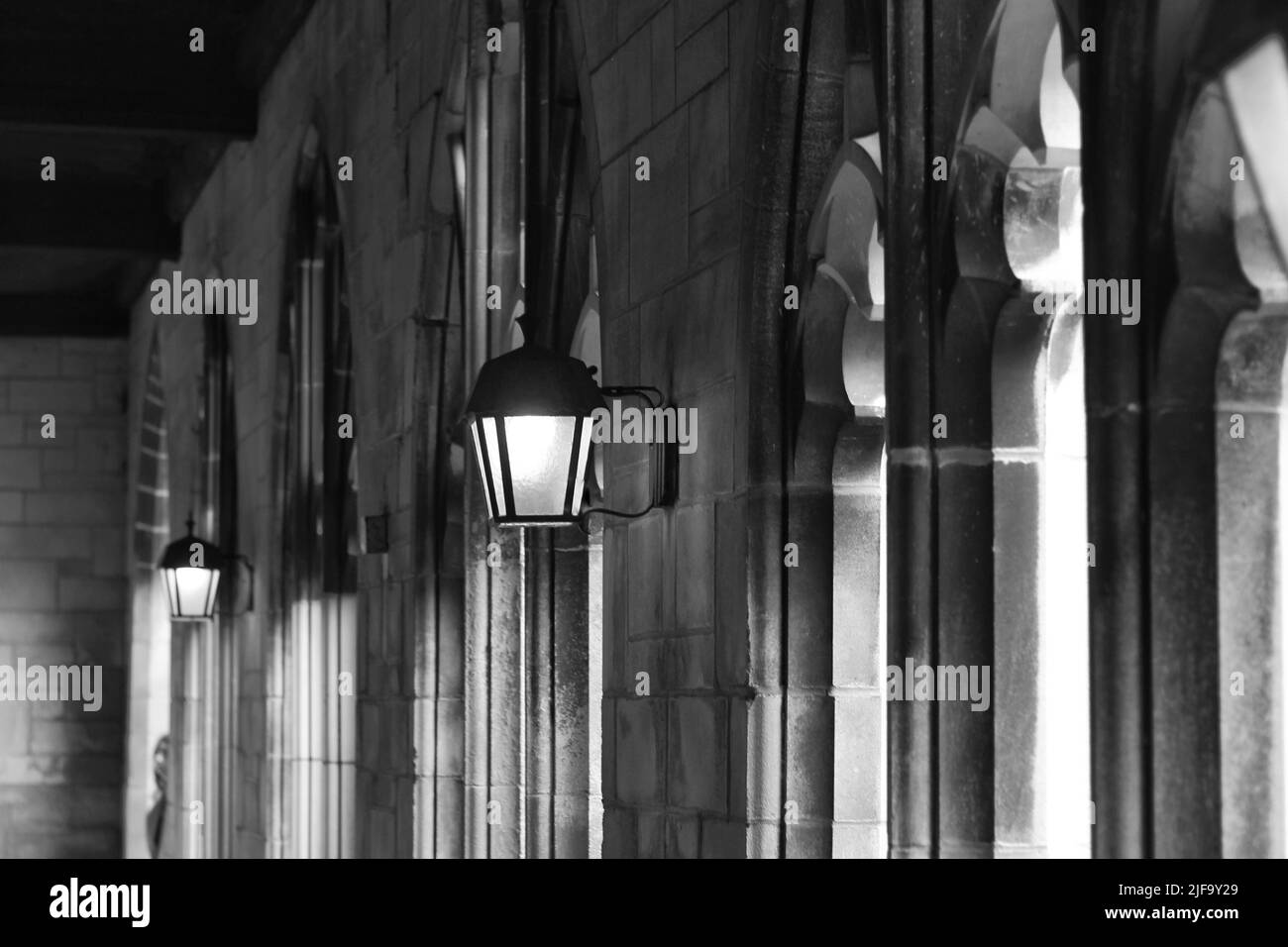 Vintage street light glowing on the old Gothic stone walls in black and ...