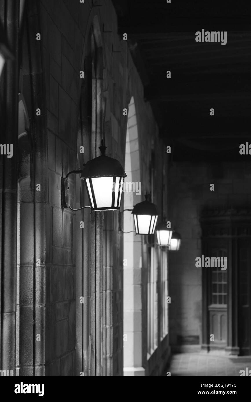 Vintage street light glowing on the old Gothic stone walls in black and ...