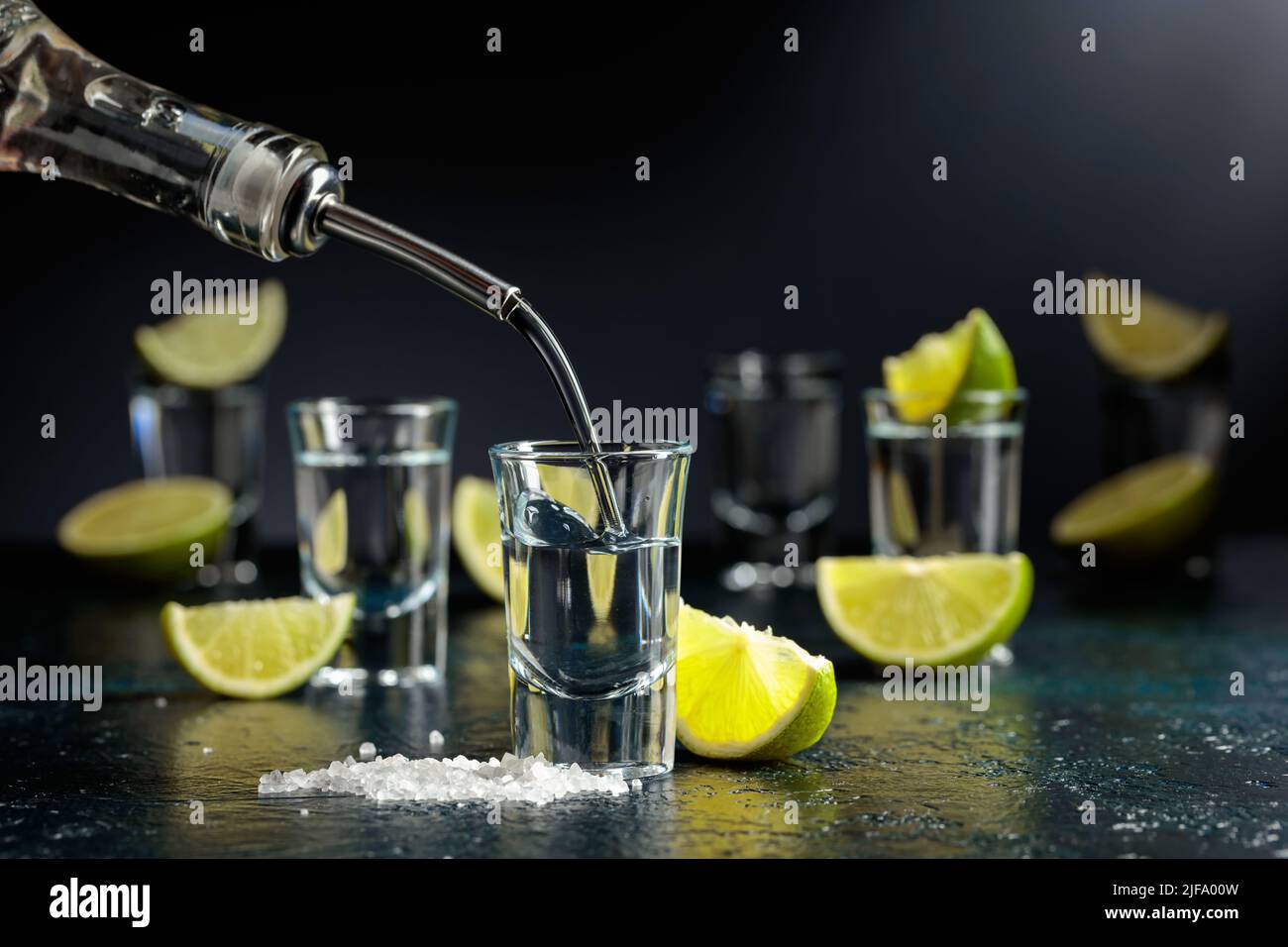 Tequila is poured into a glass. Tequila shots with lime slices and sea ...