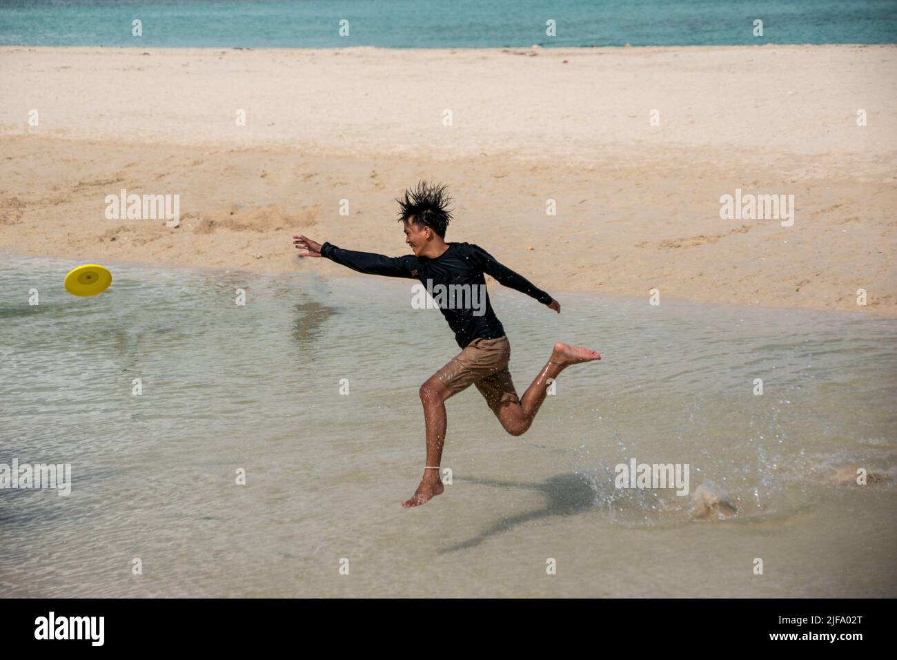 A boy happily playing with friends and trying to catch the frisbee ...
