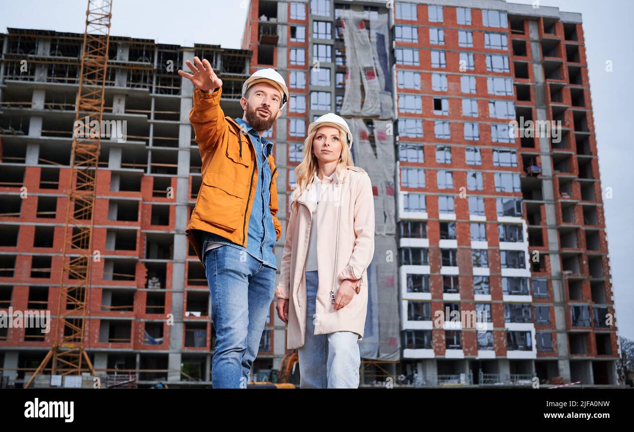 Couple in safety helmets standing outside apartment building under ...