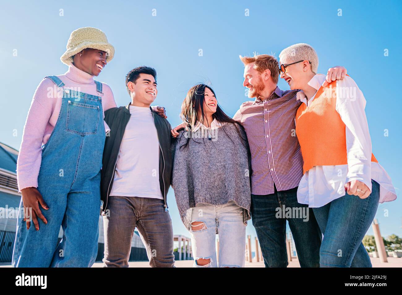 Portrait of happy friends standing with arms around each other's shoulders. Group Of Multiracial ...