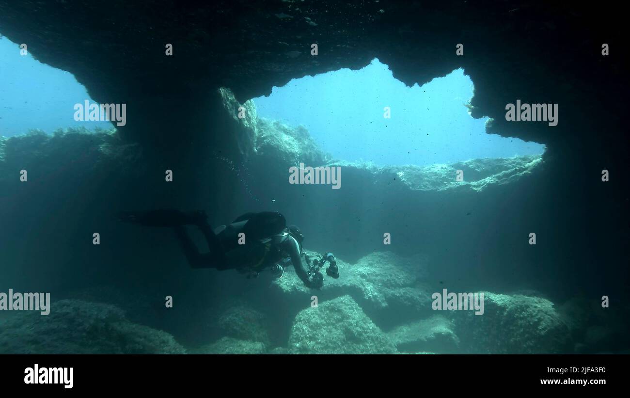 Scuba diver photographer swim in the cave. Cave diving in Mediterranean ...
