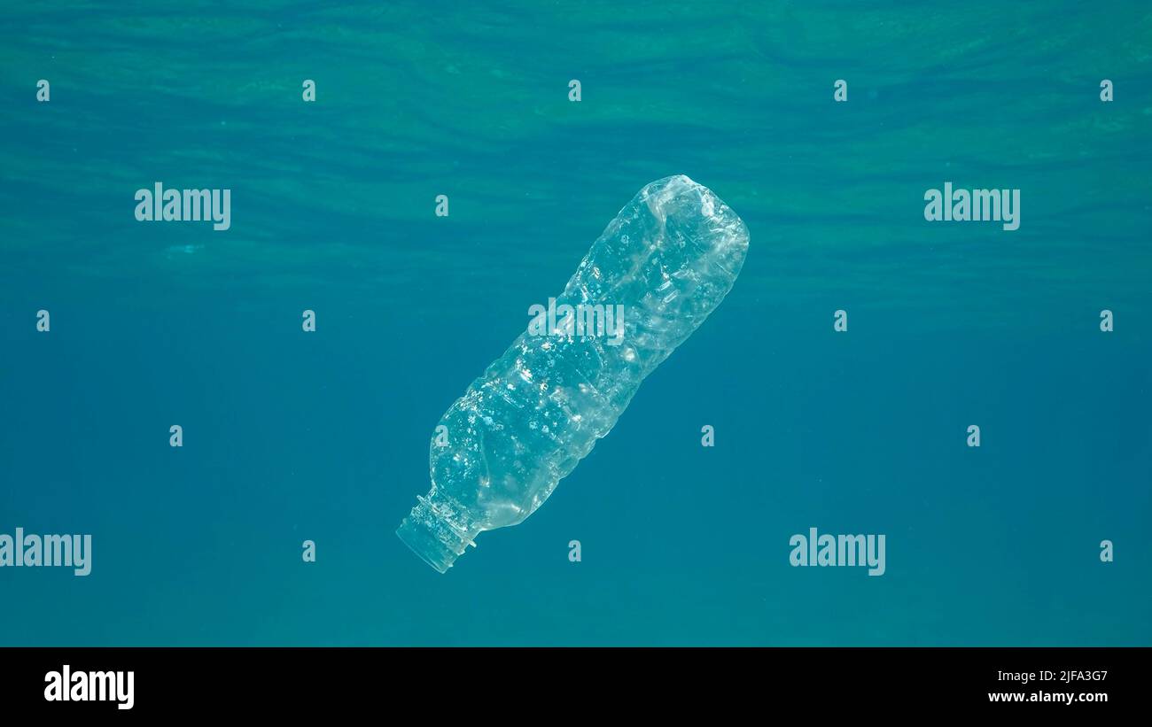 Plastic pollution, plastic bottle in blue water. Discarded plastic ...