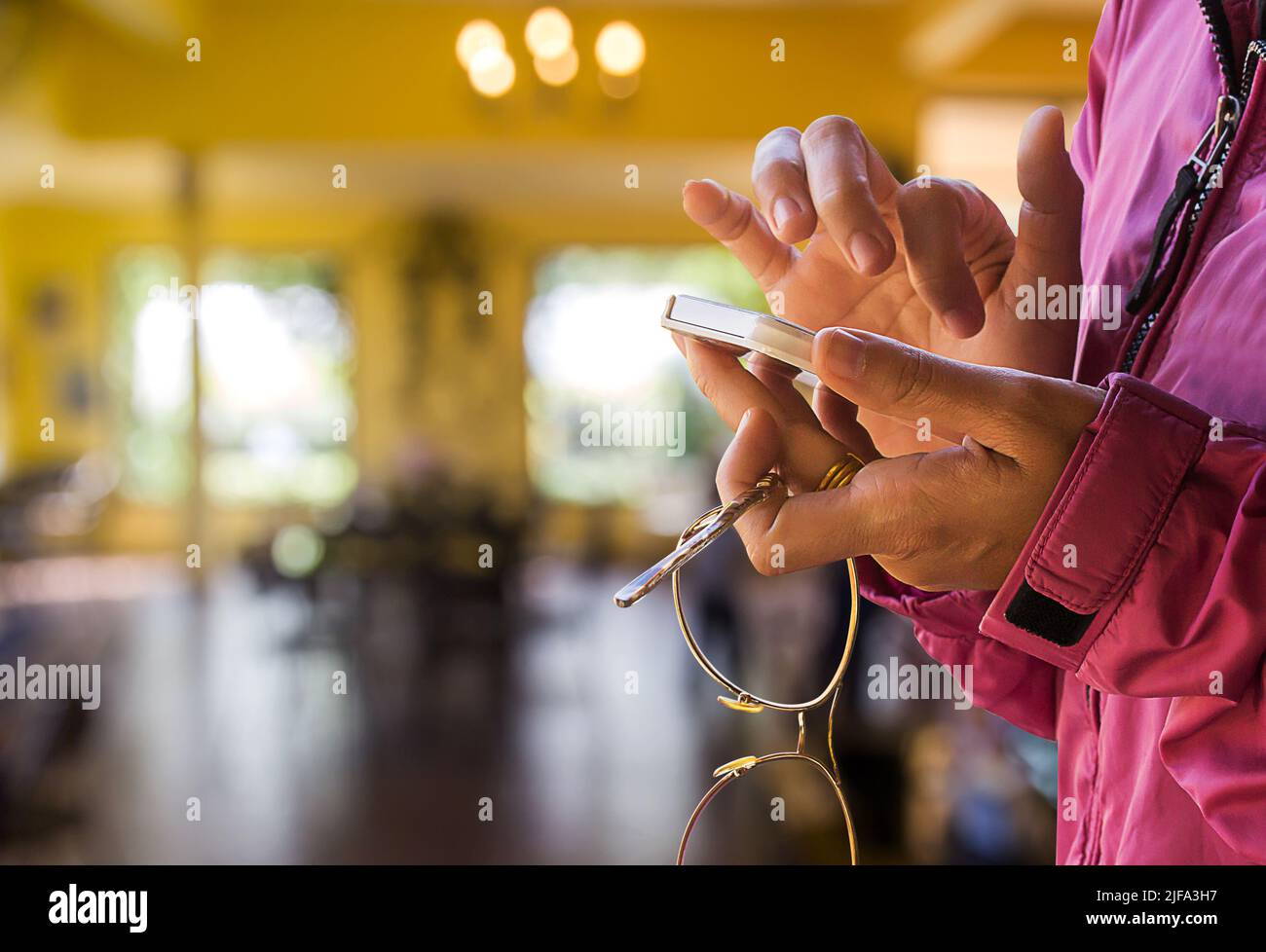 Female hand holding playing smart phone with coffee shop blur ...