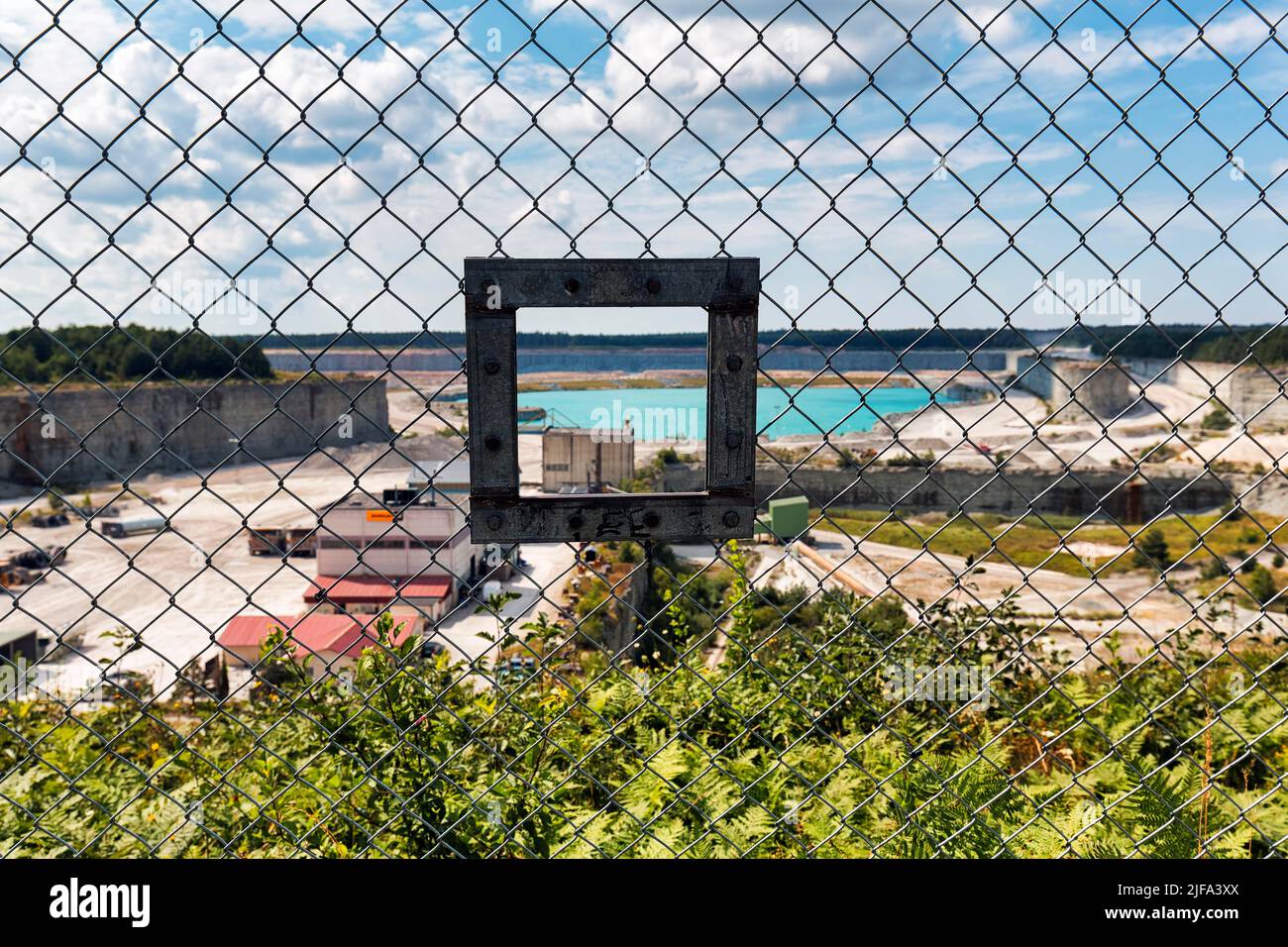 Limestone quarrying area, view through window in wire mesh fence onto ...