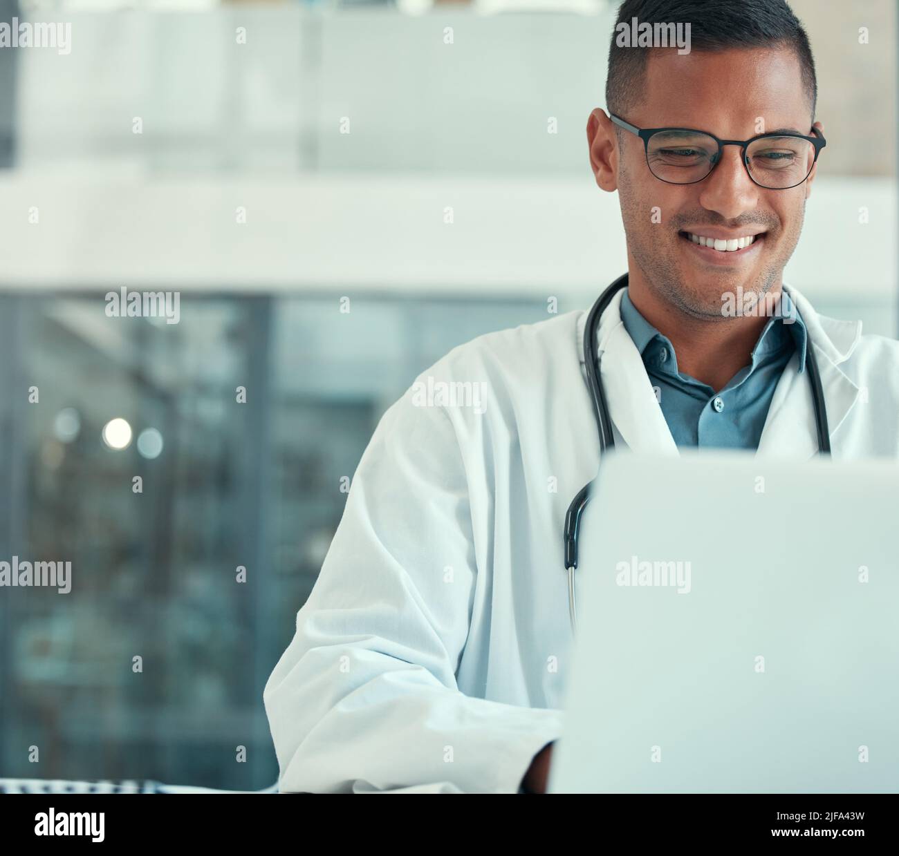 Medical doctor working on his laptop. Young doctor typing on his laptop ...