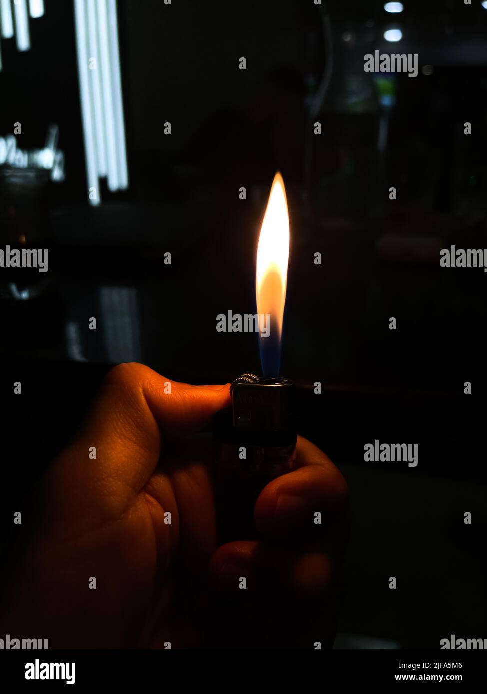 A Human hand igniting a lighter with dark background Stock Photo - Alamy