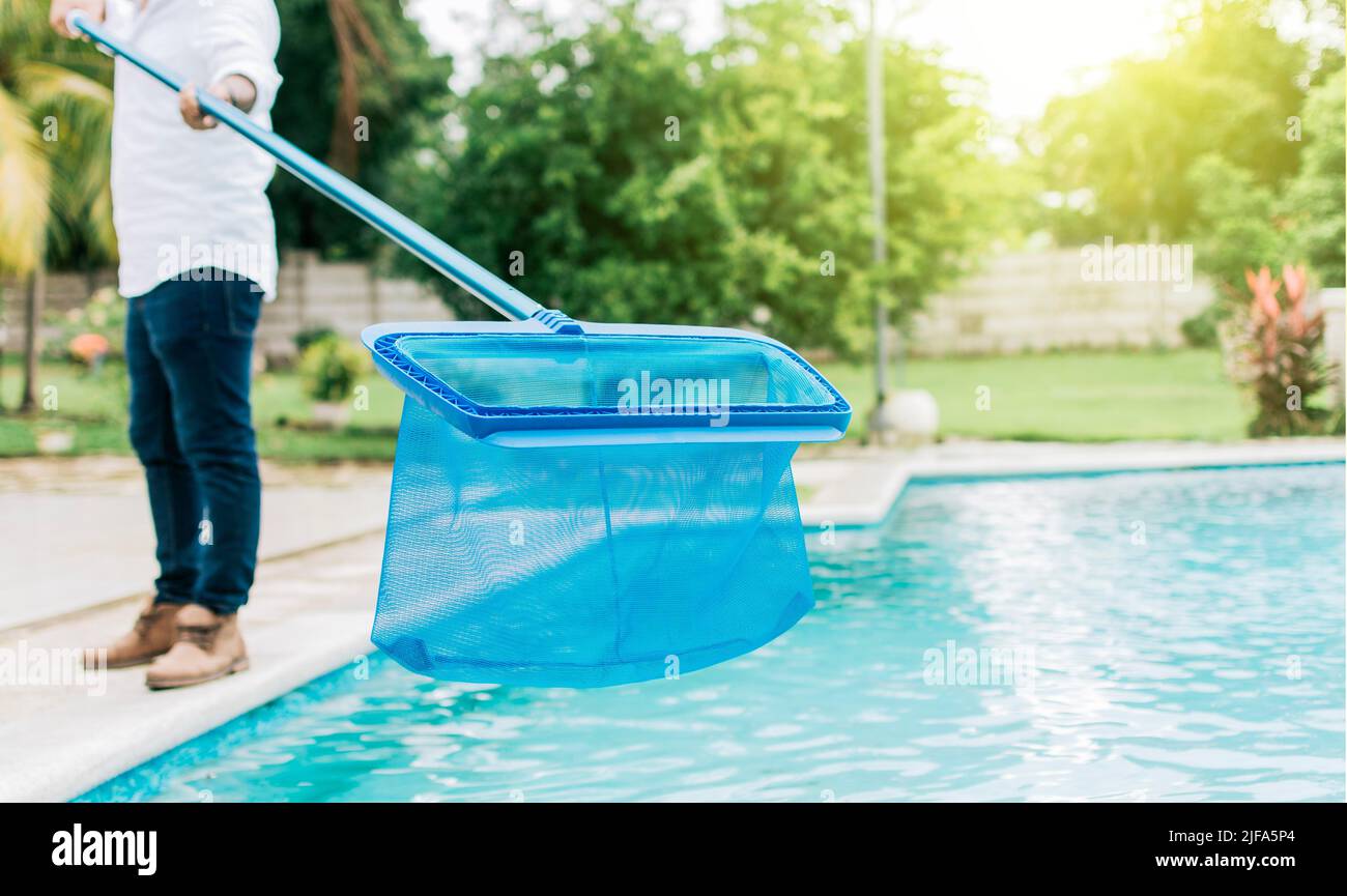 Man cleaning the pool with the Skimmer, A man cleaning pool with leaf ...