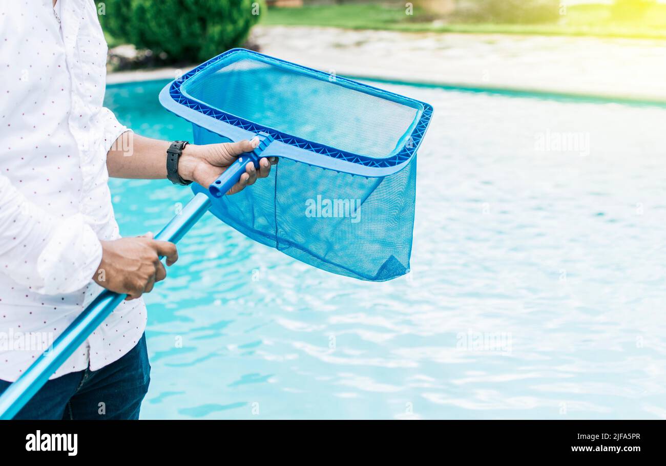 Hands holding a skimmer with blue pool in the background. A man ...