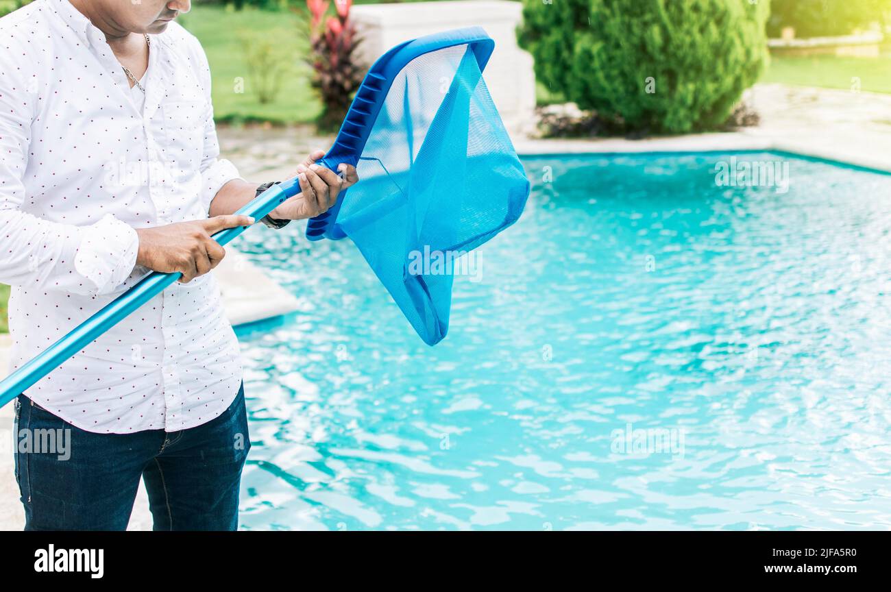 Hands holding a skimmer with blue pool in the background, A man ...