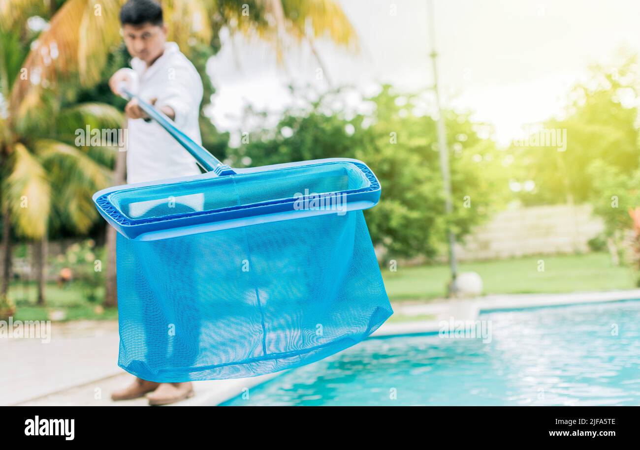 Person with skimmer cleaning pool. Man cleaning the pool with the ...