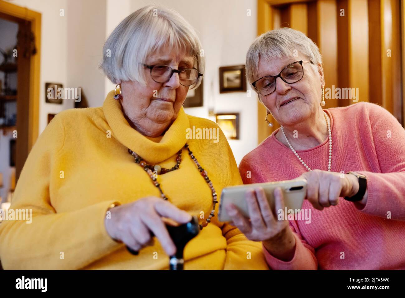 Two senior citizens, sisters, looking at a smartphone at home, Bocholt ...