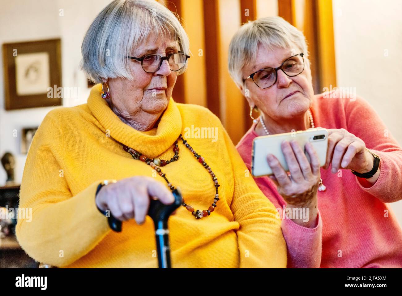 Two senior citizens, sisters, looking at a smartphone at home, Bocholt ...