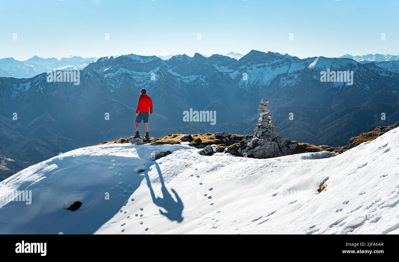 Mountaineer next to a cairn, in front of snowy mountains of the Rofan ...