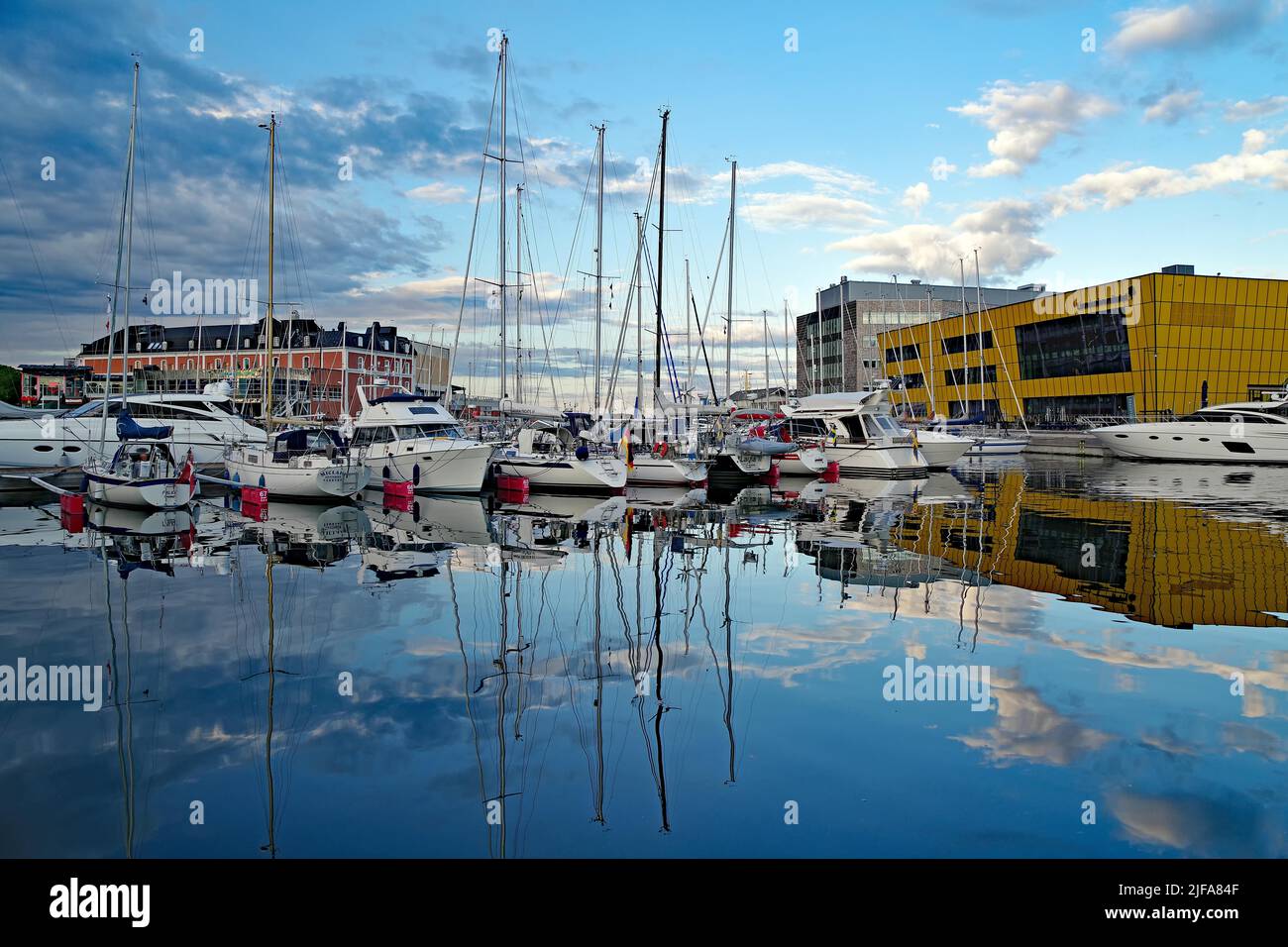 Boats, yachts and new buildings reflected in the sea, dramatic clouds ...
